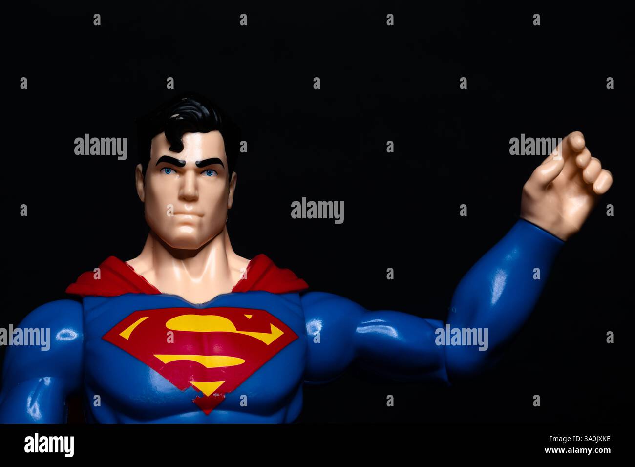 Superman action figure holding arm up isolated on black background with ...