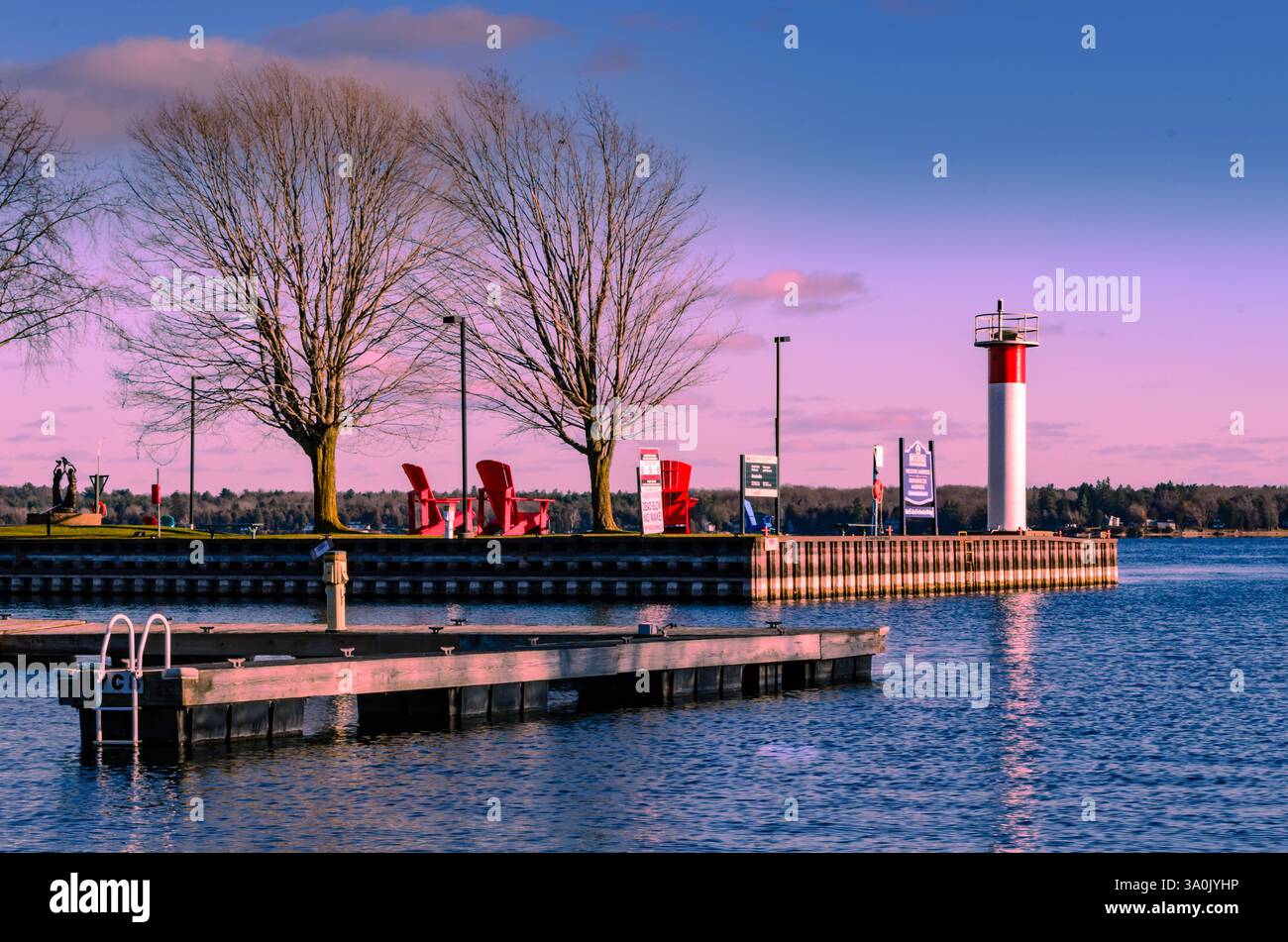 Early evening view of empty boat slips and a lighthouse beacon against ...