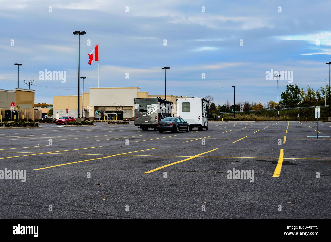 RV's in empty mall parking lot with a Canada flag against a blue sky ...