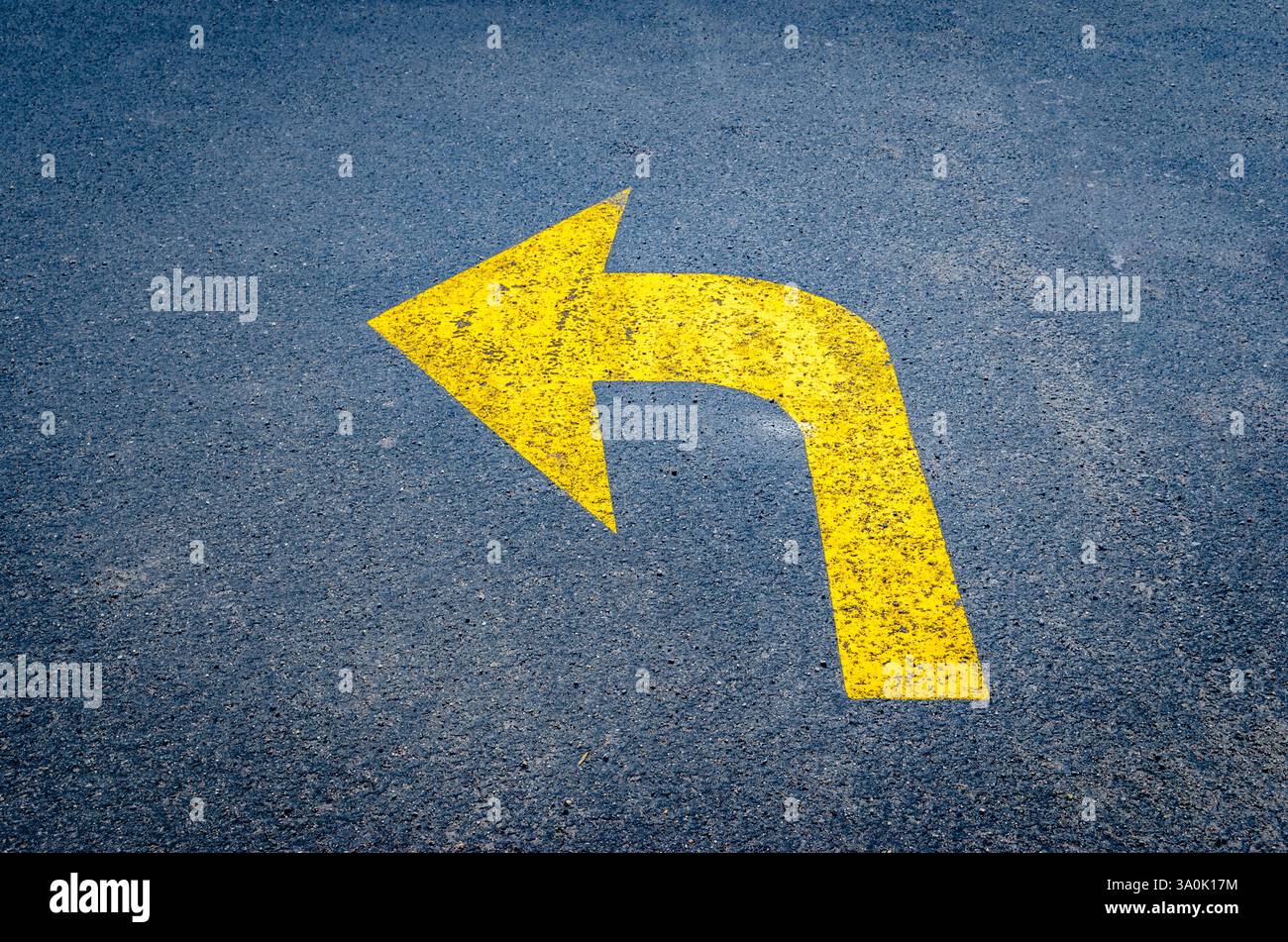Yellow arrow on black pavement pointing left Stock Photo - Alamy