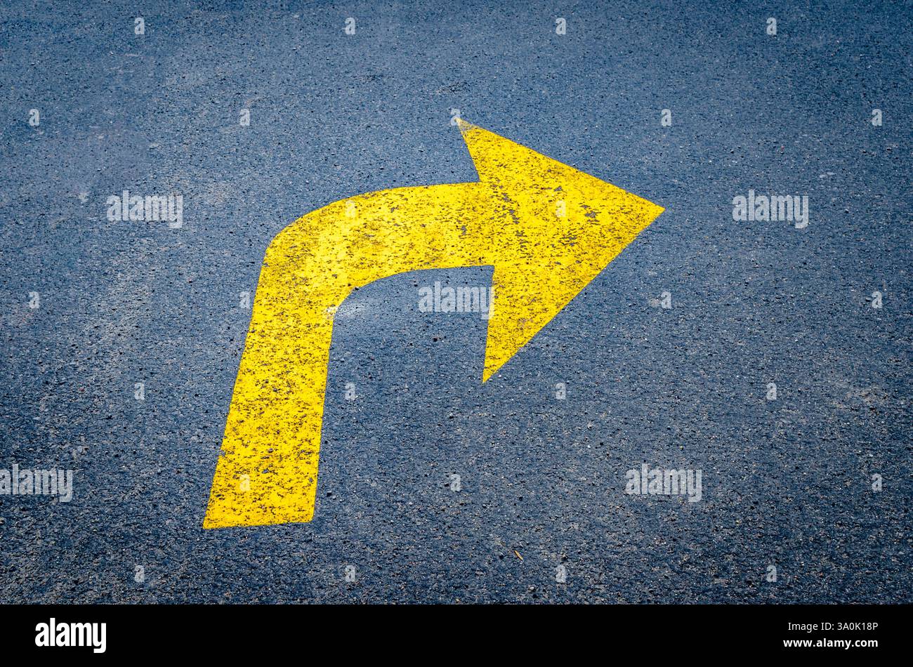 Yellow arrow on black pavement pointing right Stock Photo - Alamy