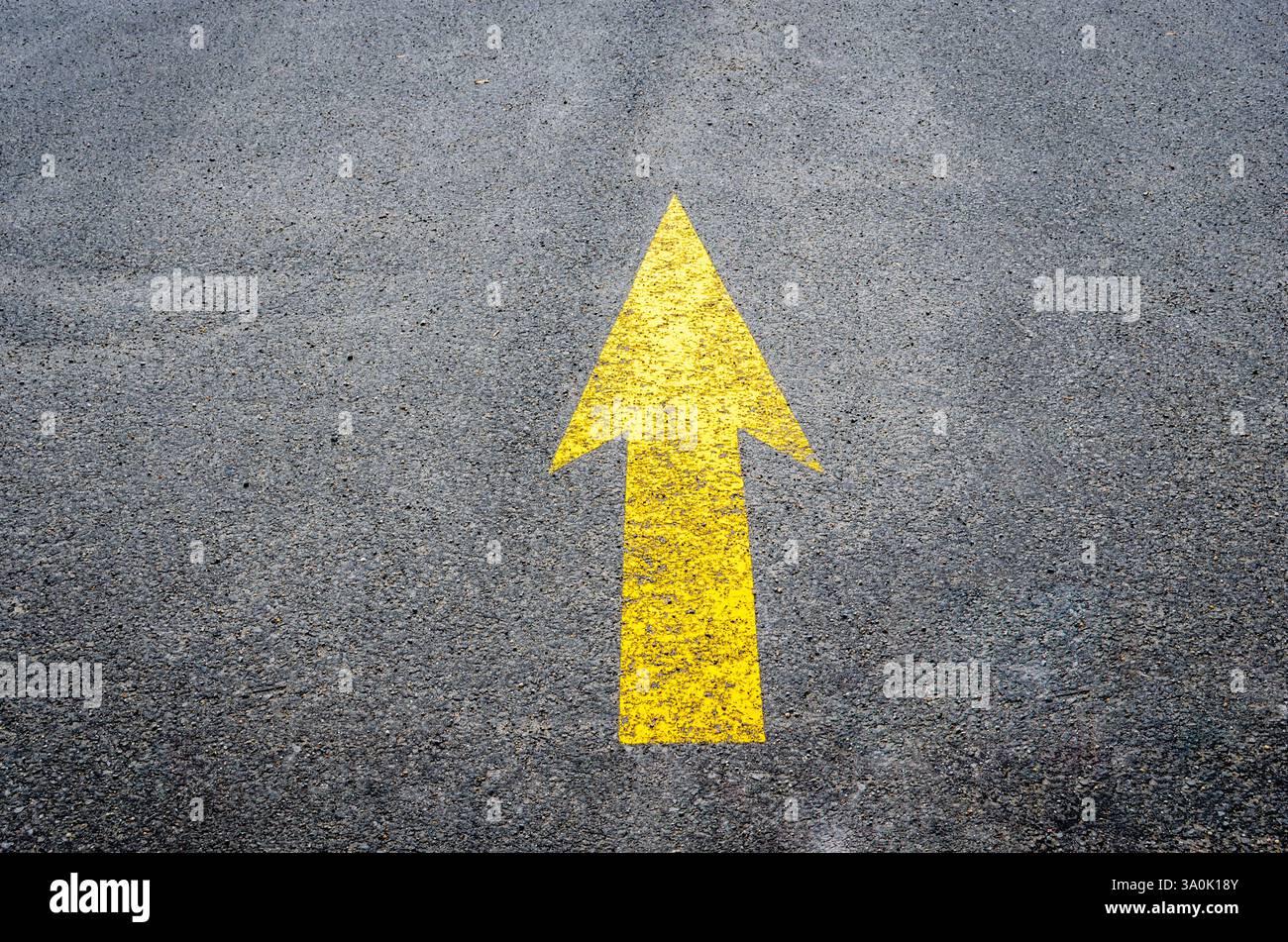Yellow arrow on black pavement pointing ahead Stock Photo - Alamy