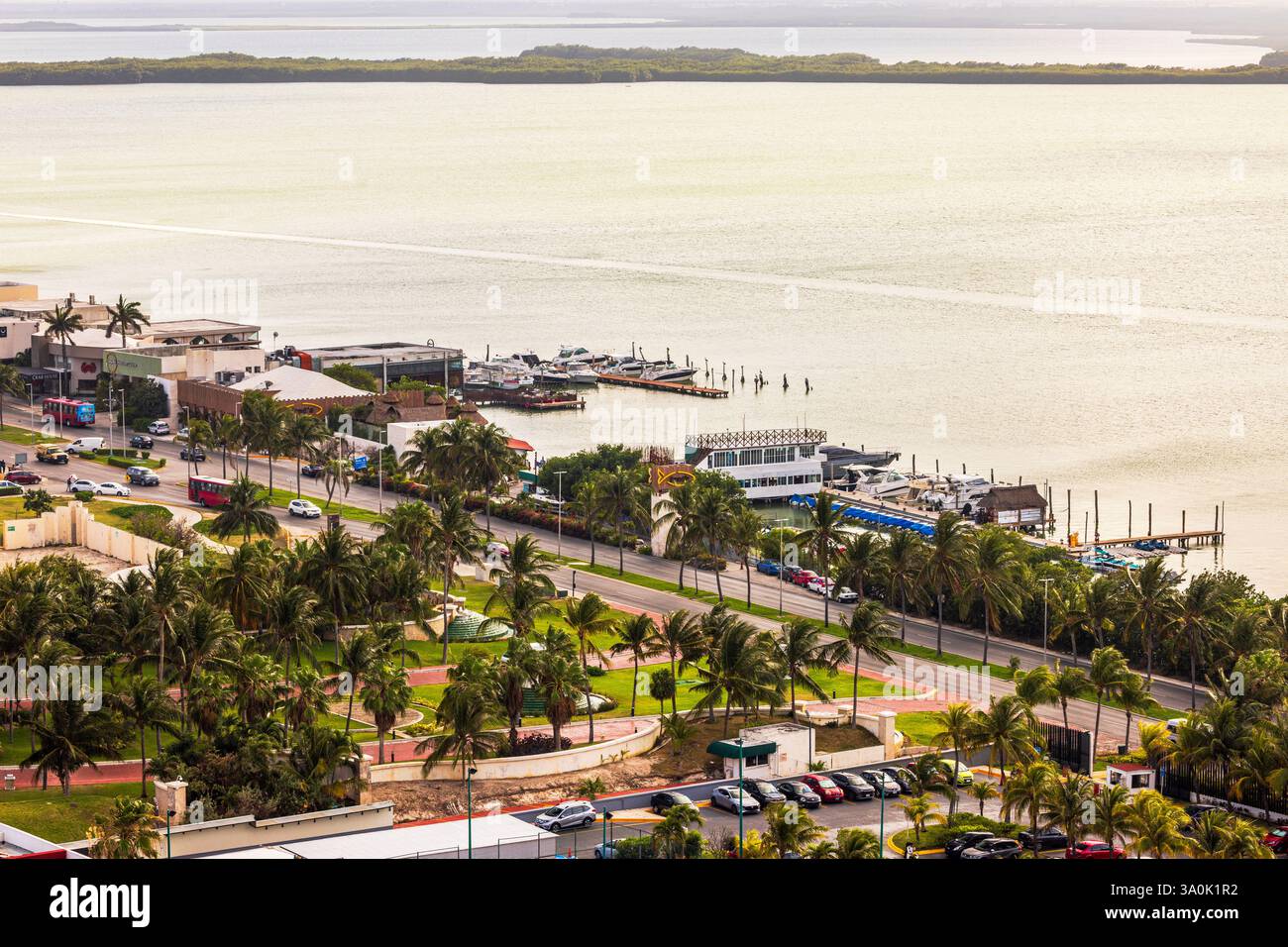 Scenic waterfront view with palm trees, marina, yachts and busy road ...