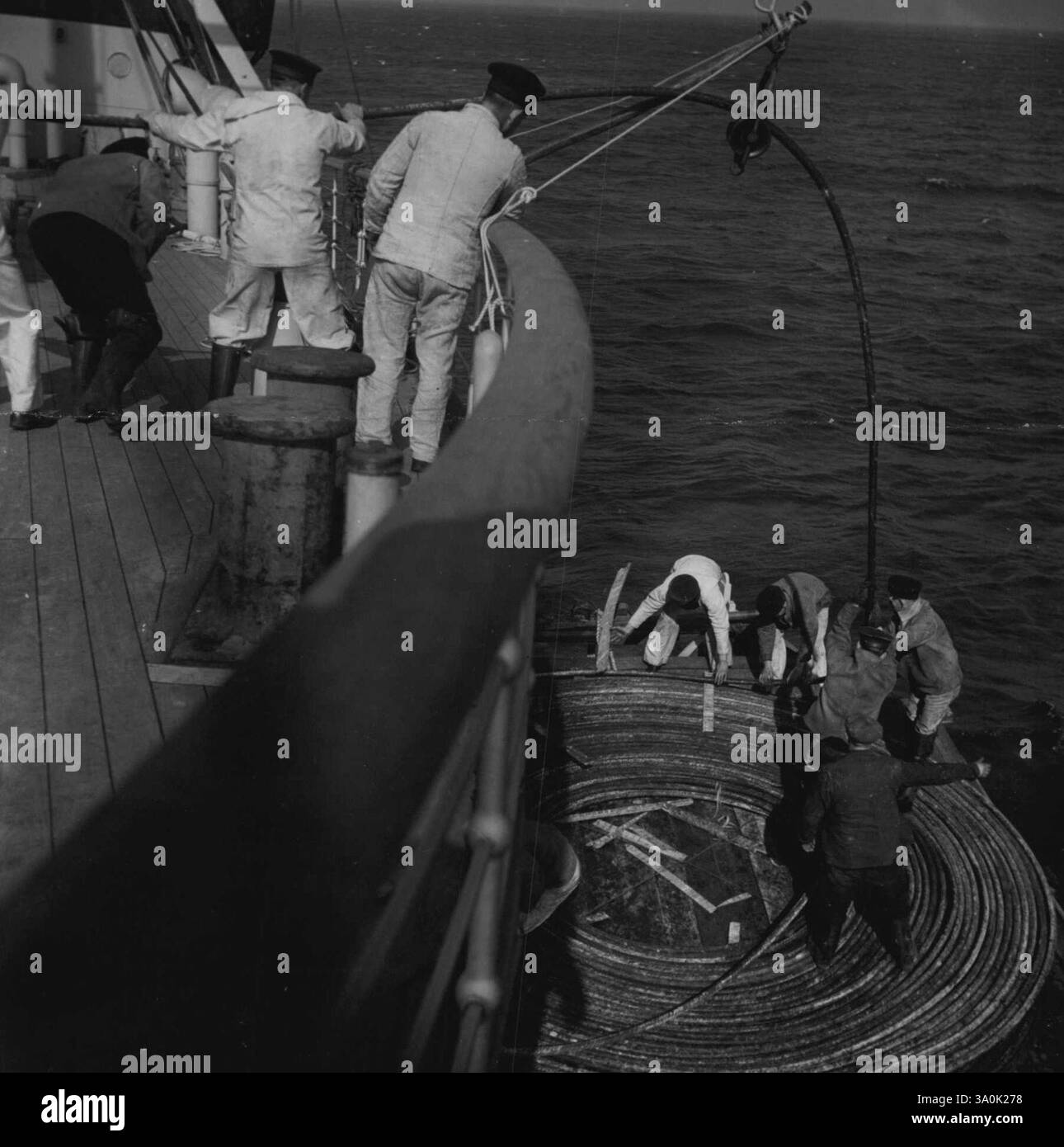 Coiling. Cable Being Coiled on a shore-raft from circular storage tanks ...