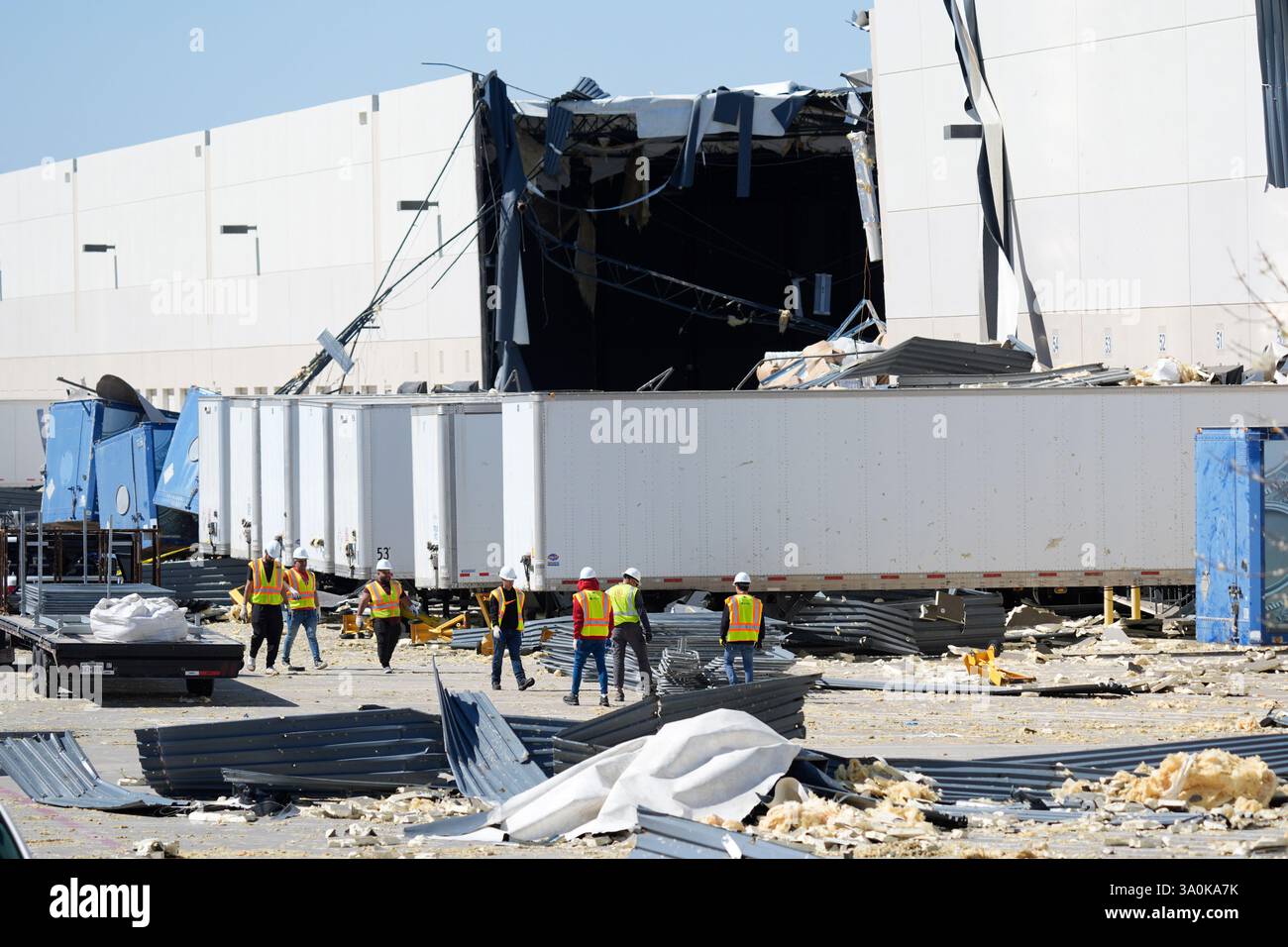 A workers walk outside a damaged warehouse after storms moved through ...