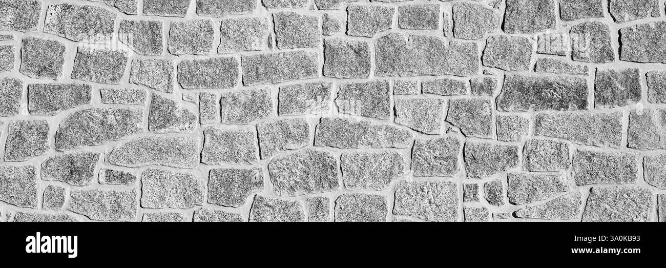 Black and white close-up of an irregular stone wall. The rough texture ...