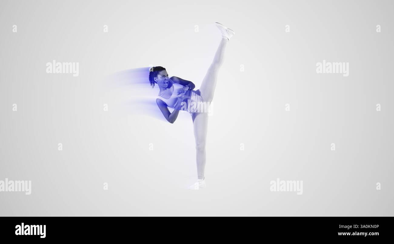 Athletic woman doing karate side kick, clenching fists and raising leg ...