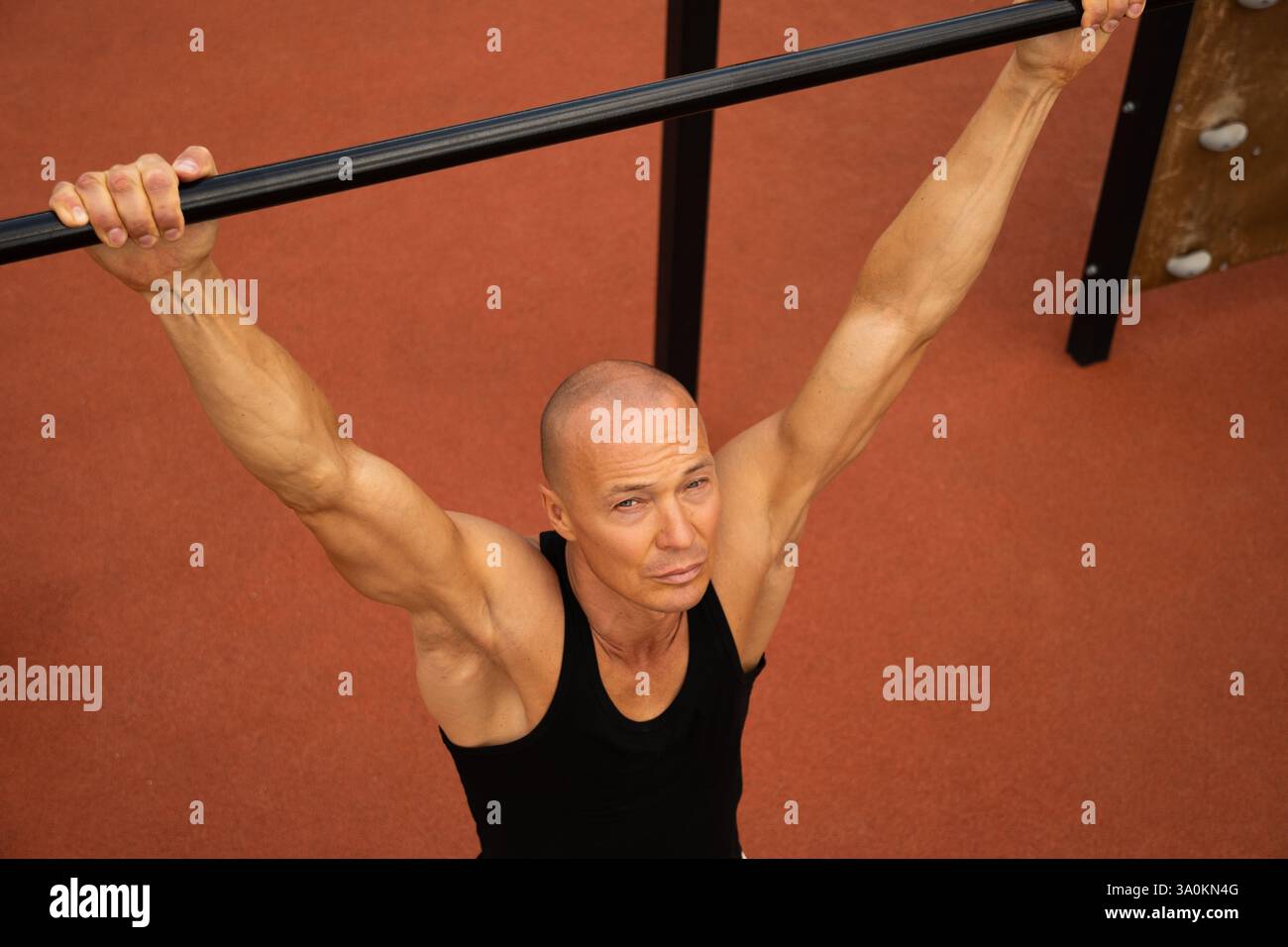 Athlete muscular fitness male pulling up on horizontal bar at street ...
