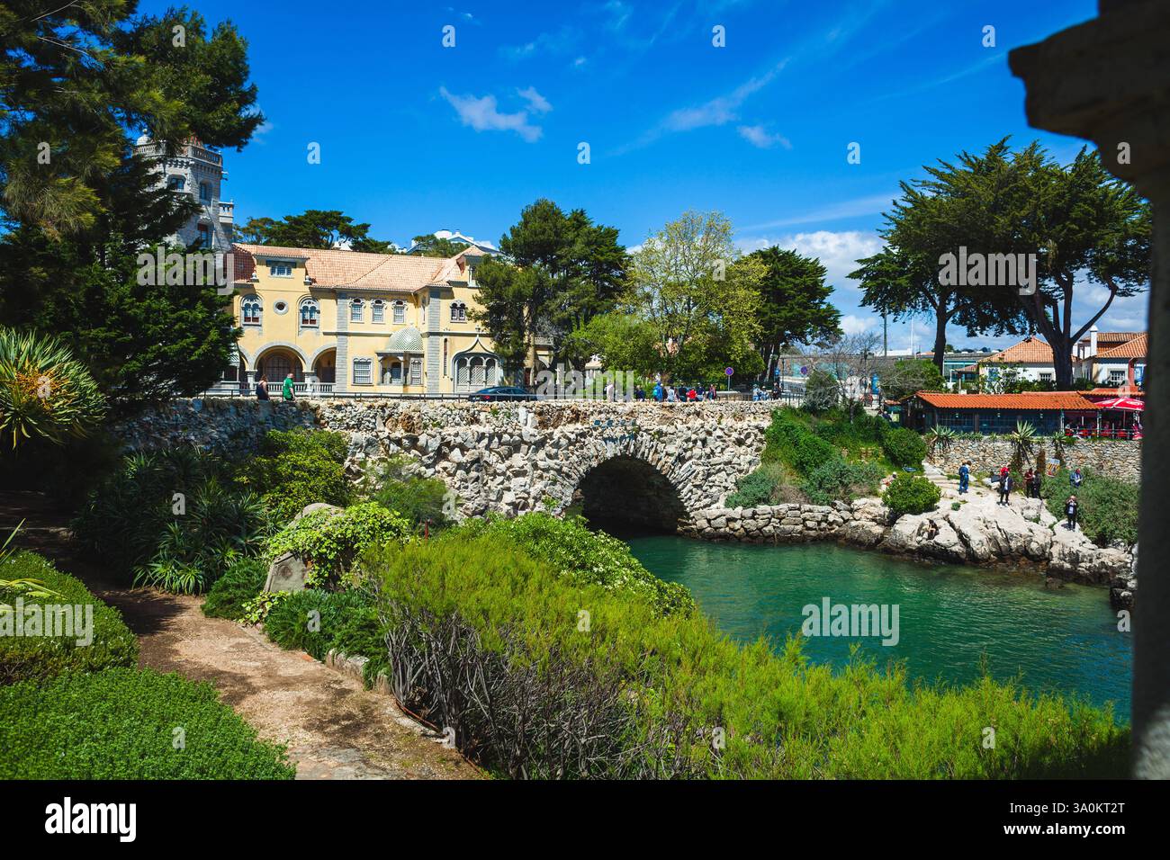 A scenic view of a historic stone bridge crossing a lush garden with a ...