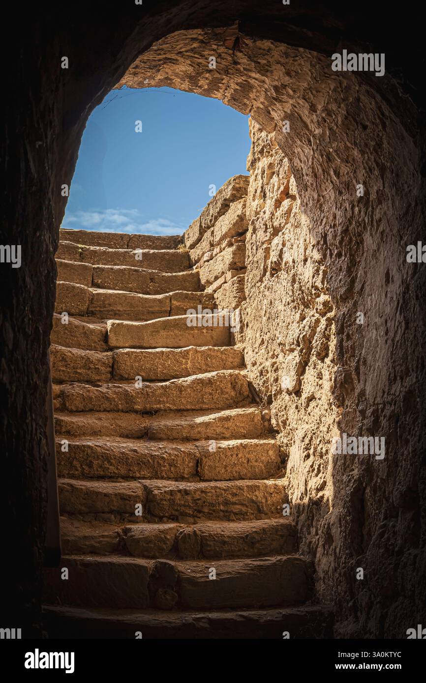 An ancient passageway with weathered stone steps ascends into bright ...