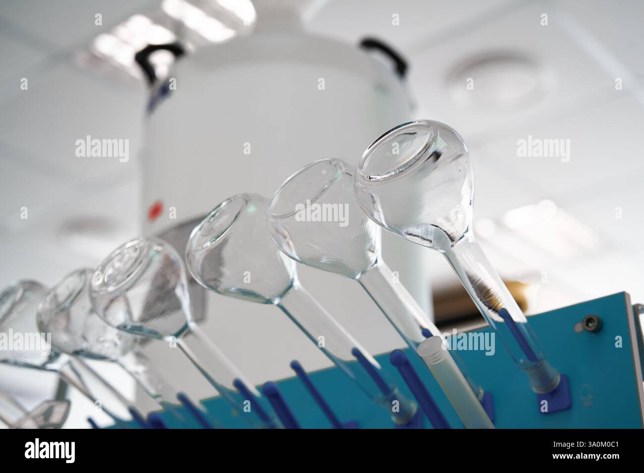 Glass laboratory equipment arranged neatly on a rack in a well-lit lab ...