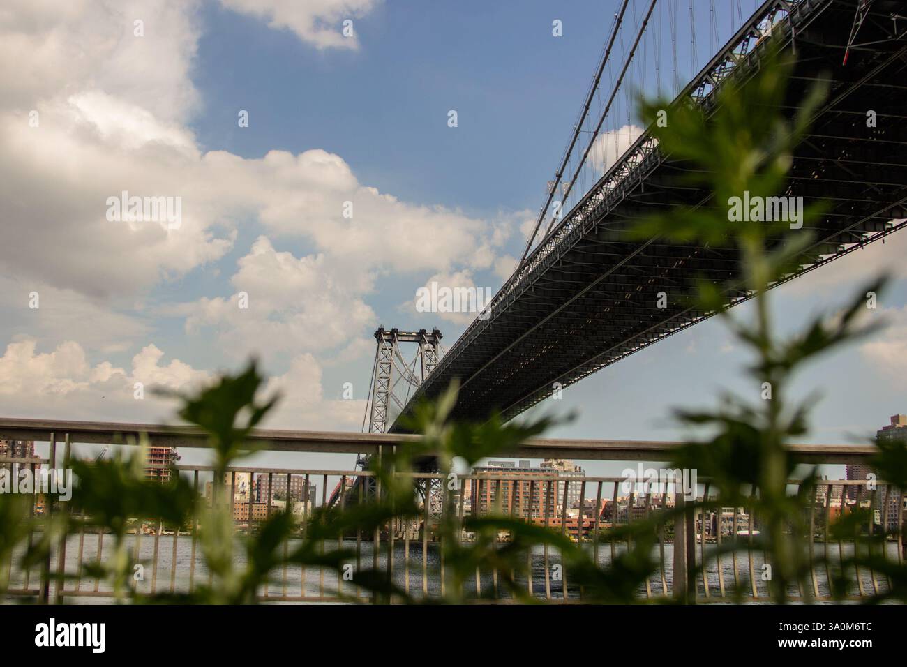 A dramatic low-angle view of williamsburg bridge in New York City contrasting glass, steel, and ...