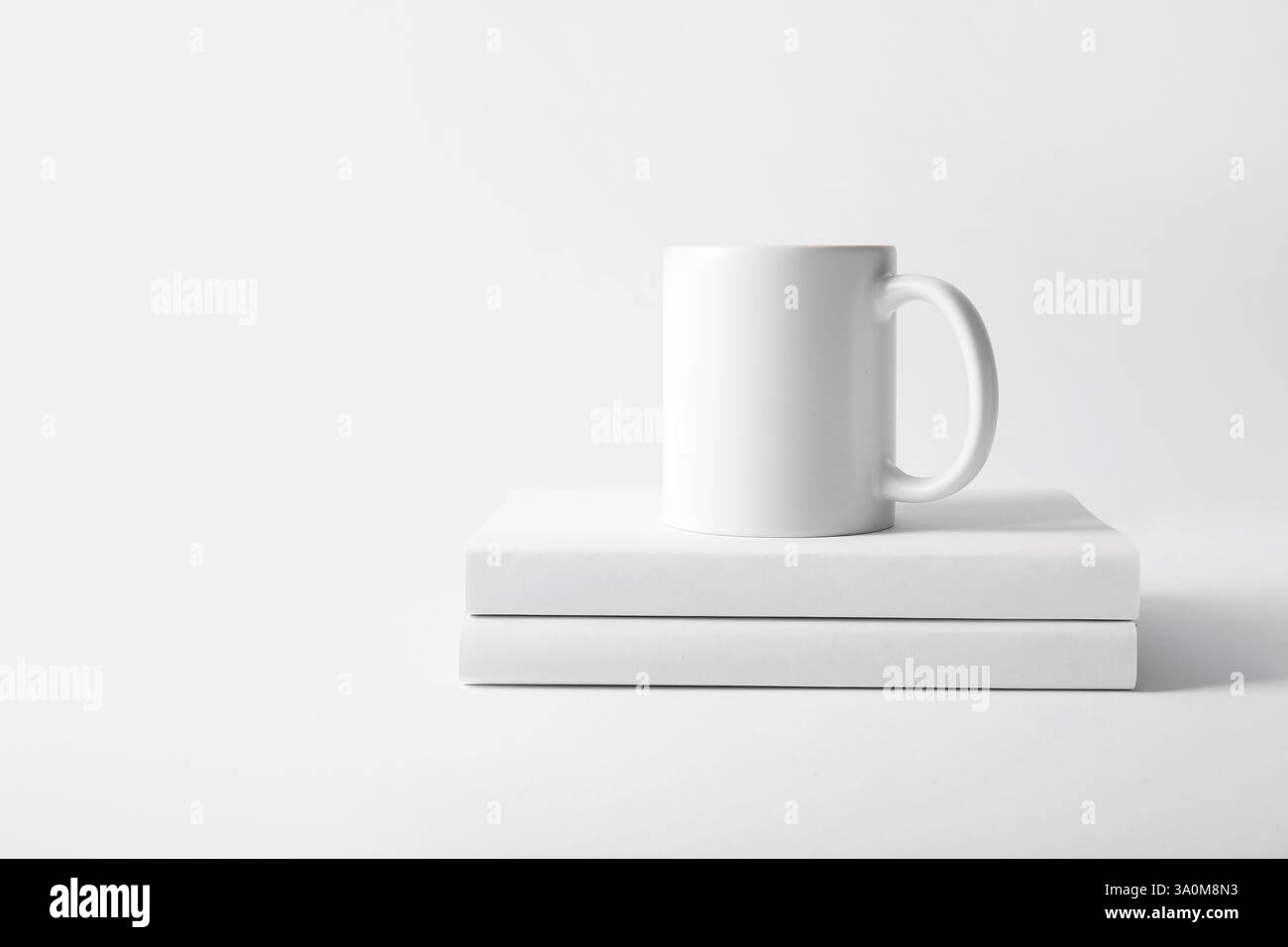 Ceramic mug on books on white background Stock Photo - Alamy