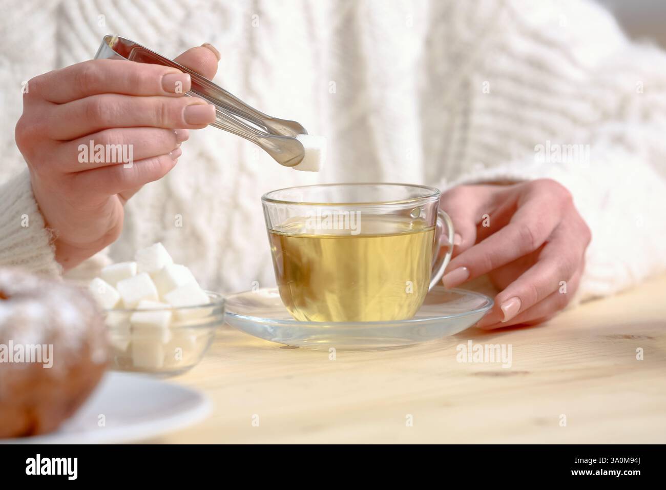 Woman putting lump of sugar into tea at table in kitchen. Closeup Stock ...