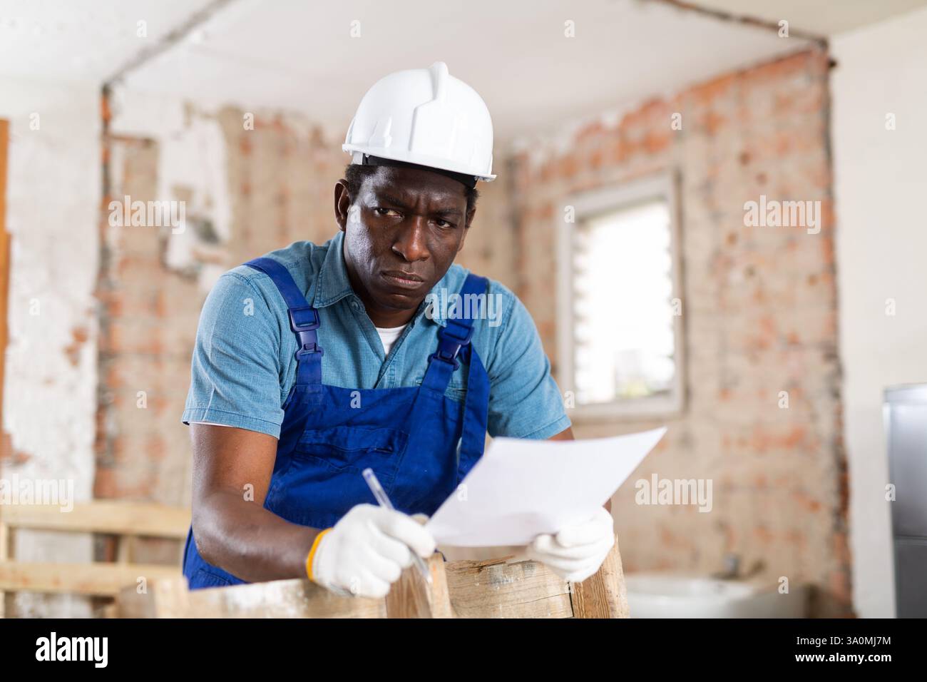 Upset african american contractor standing with papers at construction ...