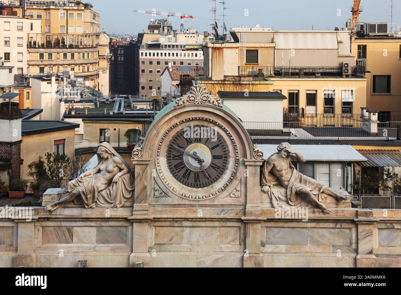 The clock with sculptures on facade of building seen from Milan Duomo ...