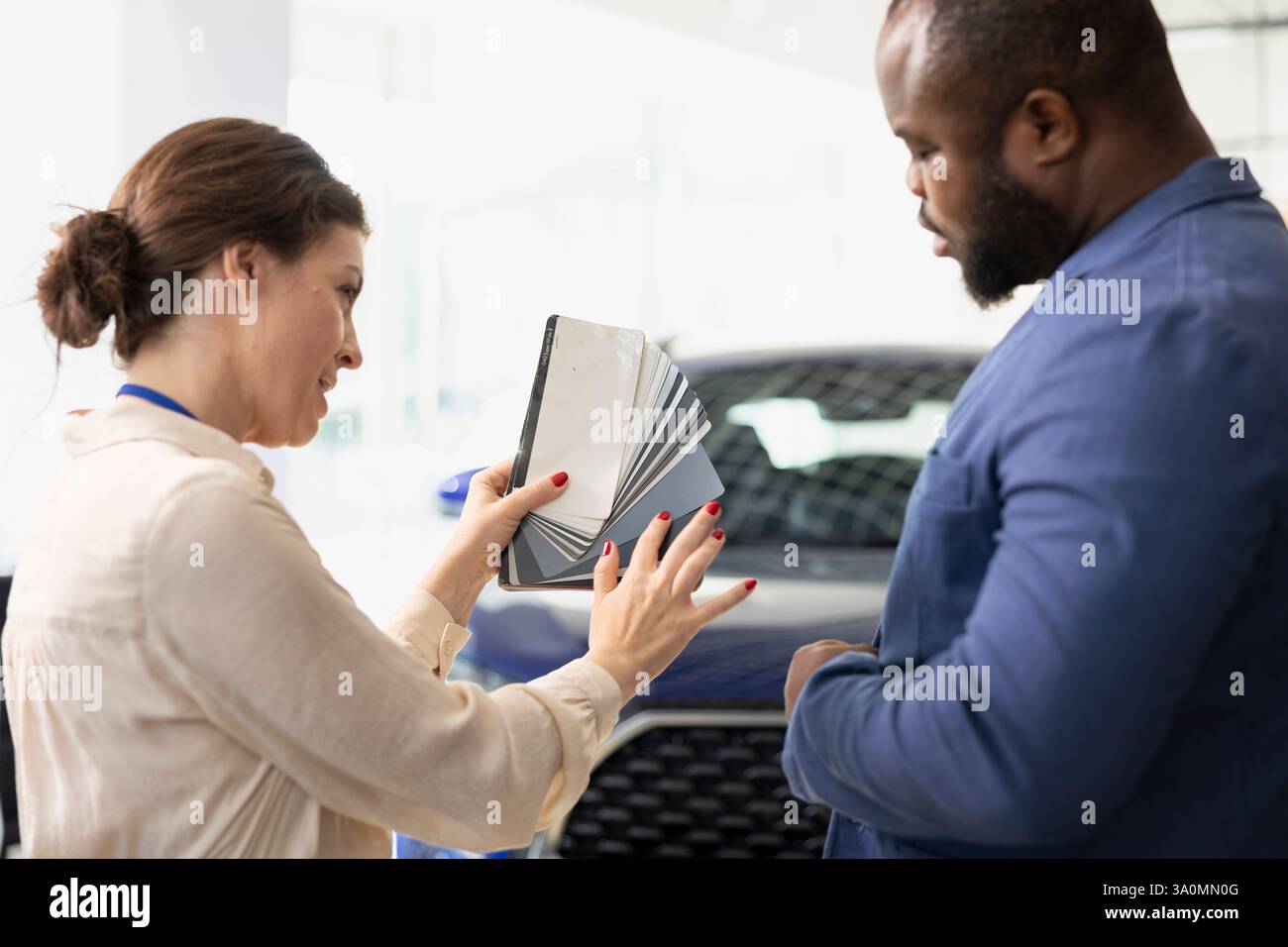 Saleswoman in dealership talking with client, offering color swatch samples choice, trying to ...