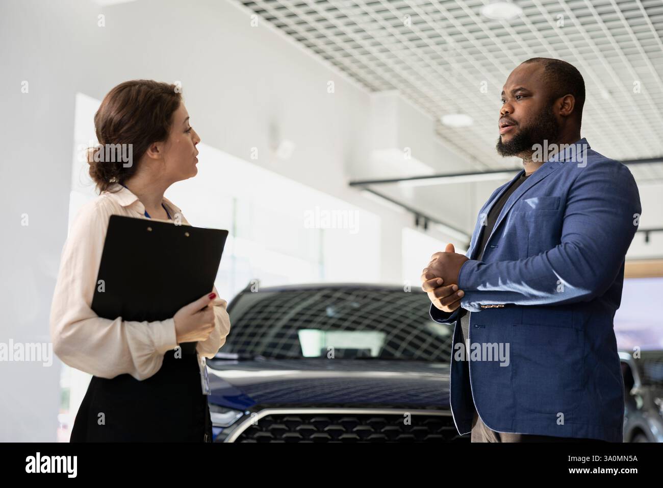 Car saleswoman showcasing dealership vehicles to man, explaining ...