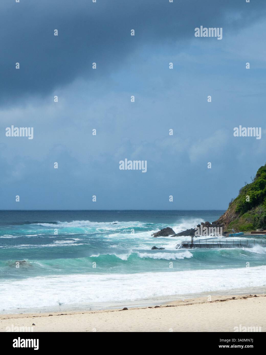 Waves crashing over the end of the pool and splashing over the edges as ...