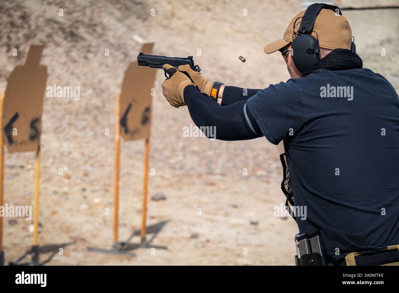 Man fires 45 caliber handgun at a California gun range, wearing a ...
