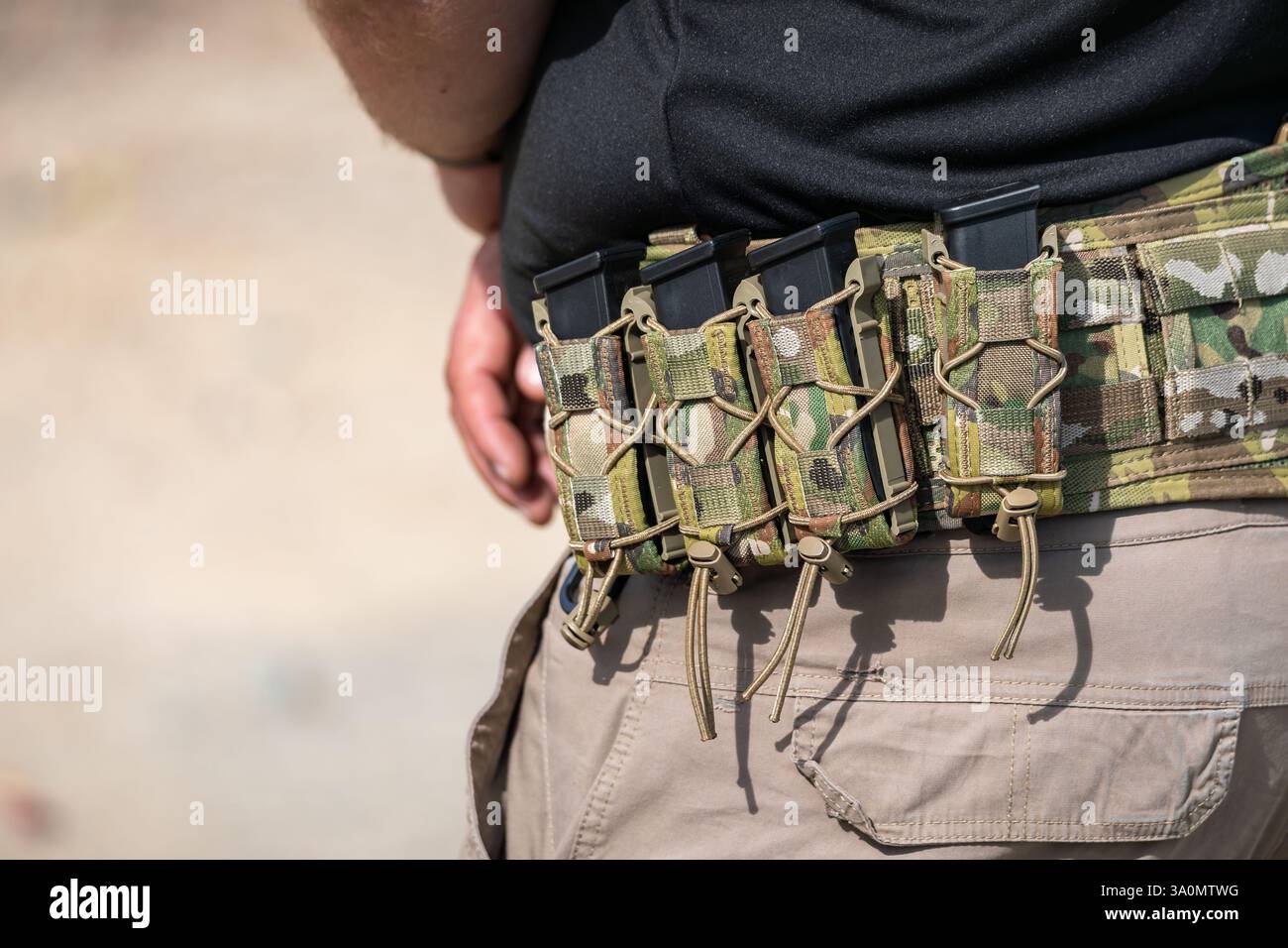 Camouflage tactical belt with multiple magazine pouches holding handgun ...