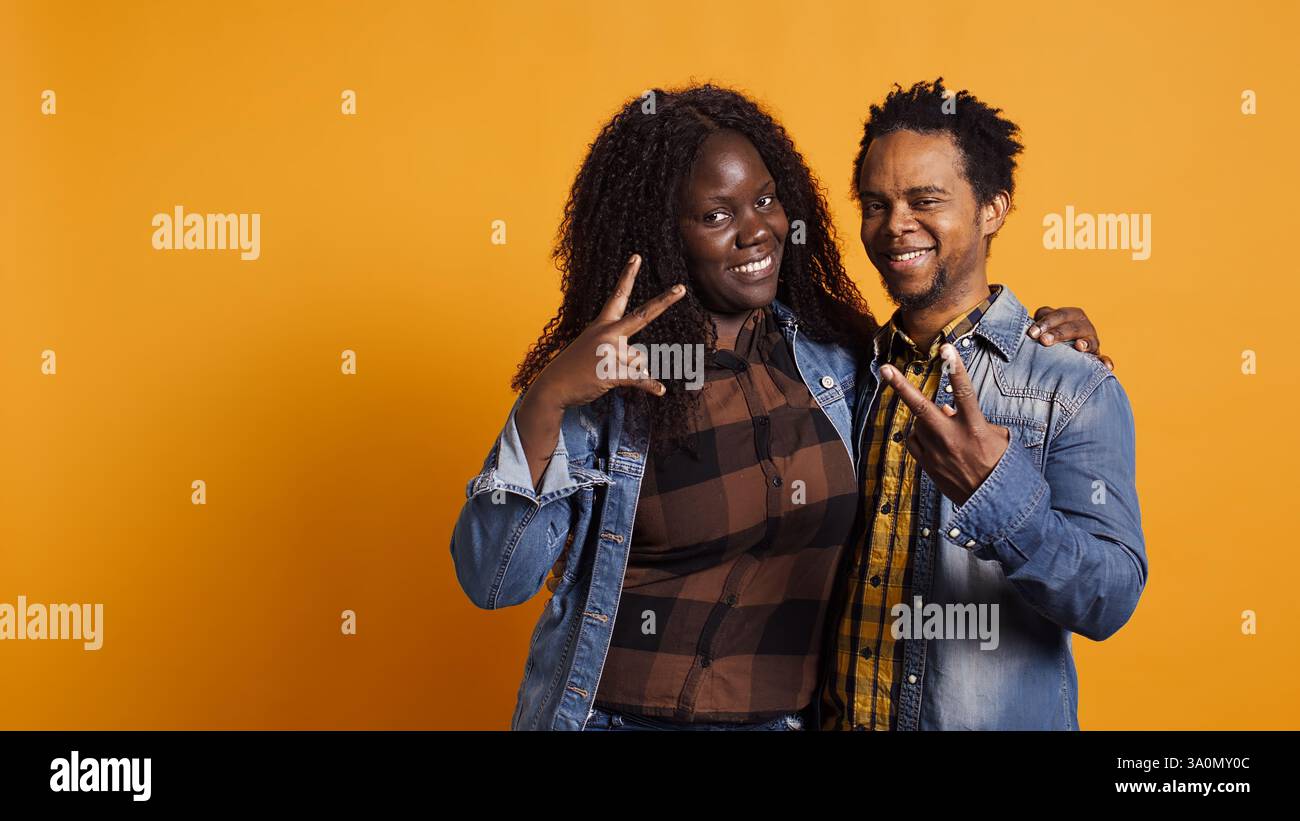 Cute life partners posing in studio and doing peace sign in studio ...