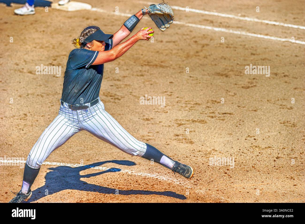 A Fast Pitch Softball Pitcher Is In Full Wind Up Pitching The Ball To ...