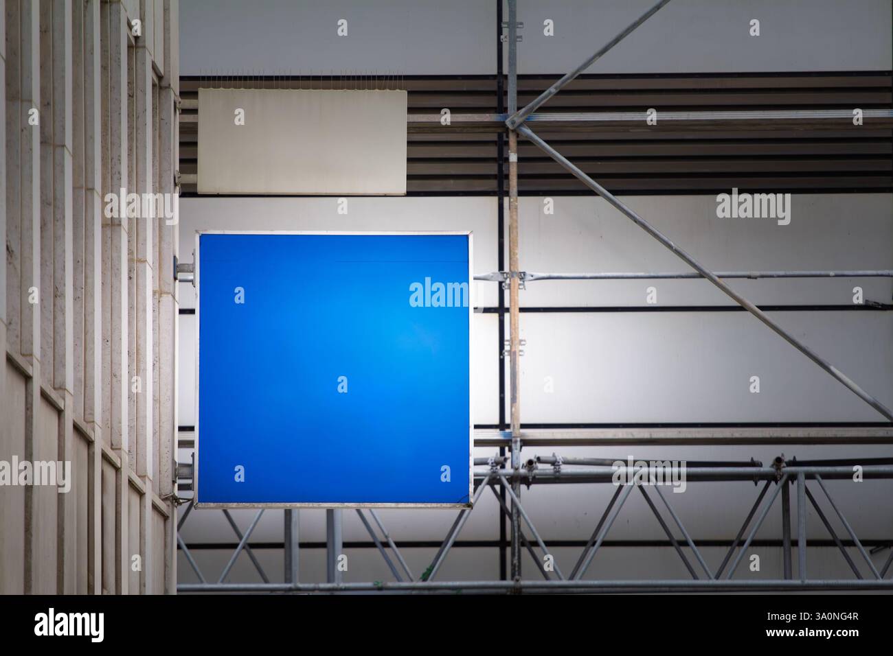 An empty blue square sign mounted on a commercial building facade in ...