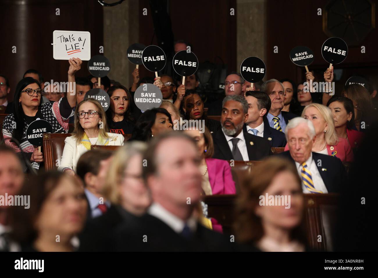 Democrats hold protest signs as President Donald Trump addresses a ...