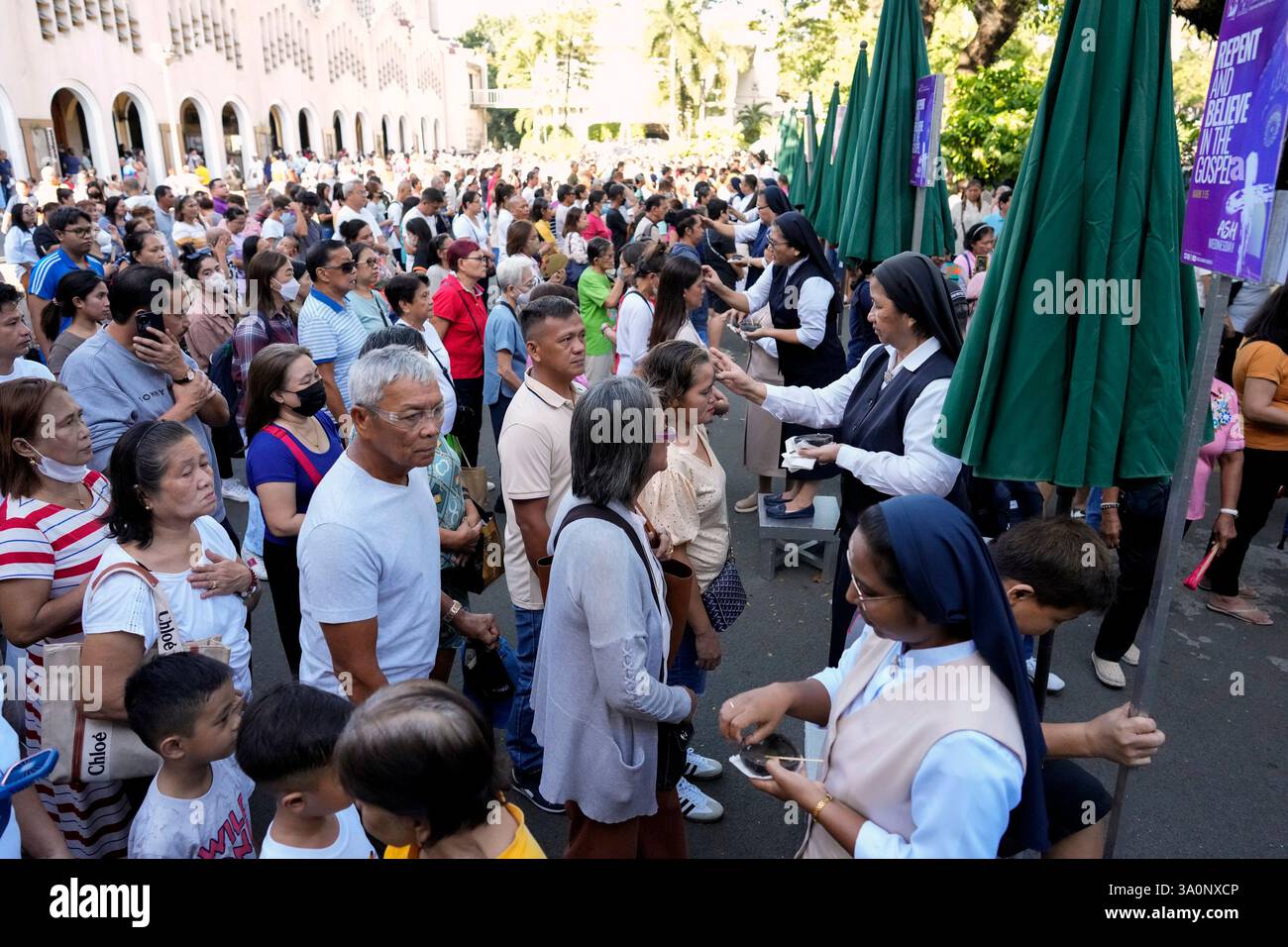 Devotees line up to be marked with an ash cross on their foreheads ...