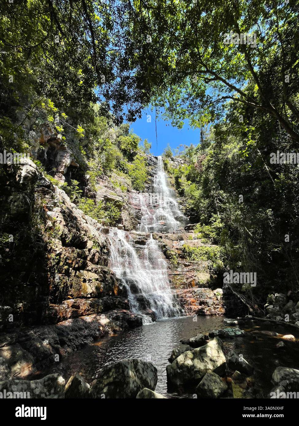 Multi-tiered waterfall flowing over rocky cliffs into a natural pool in ...