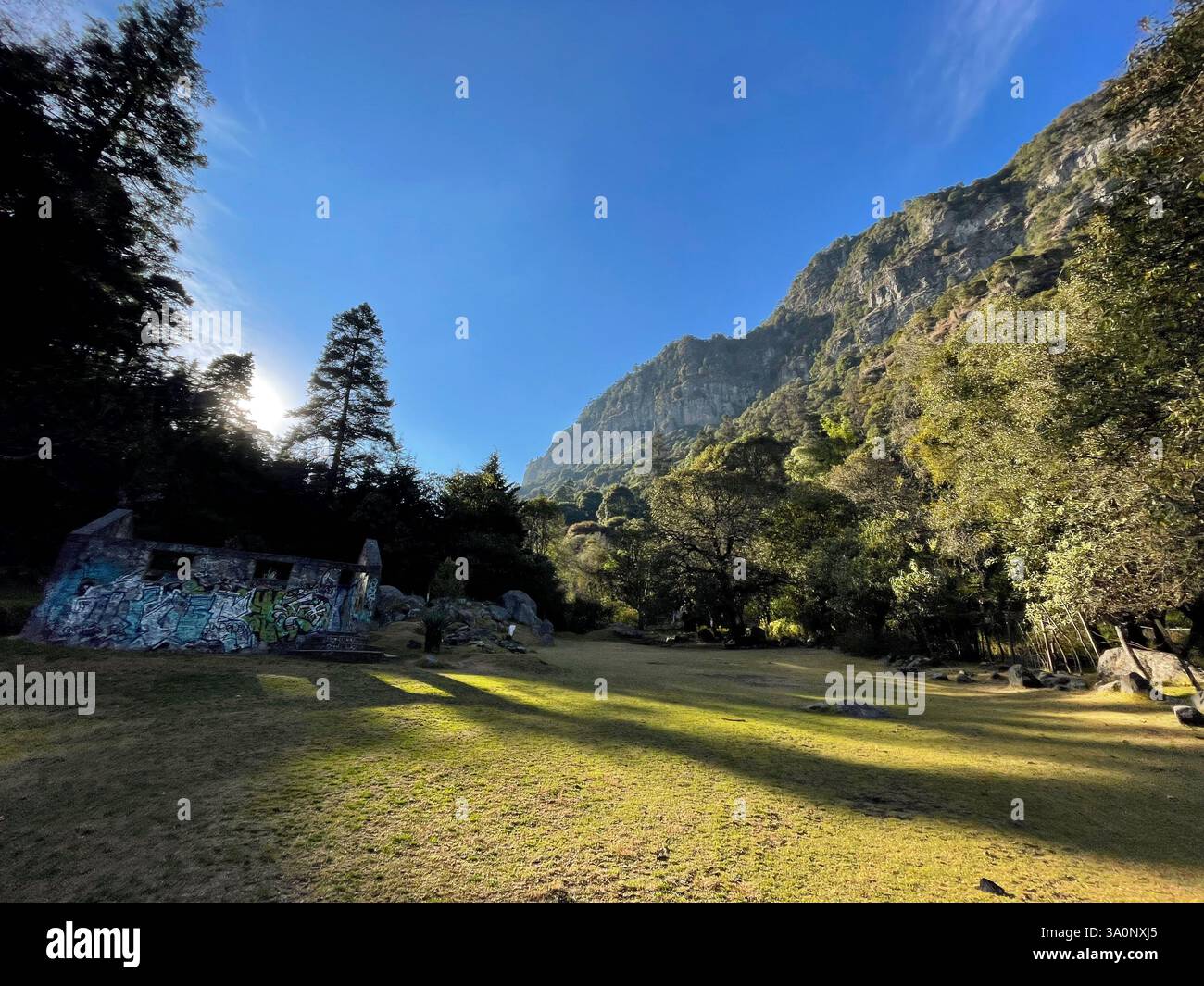 Graffiti-covered ruins in a green valley beneath towering mountains on ...