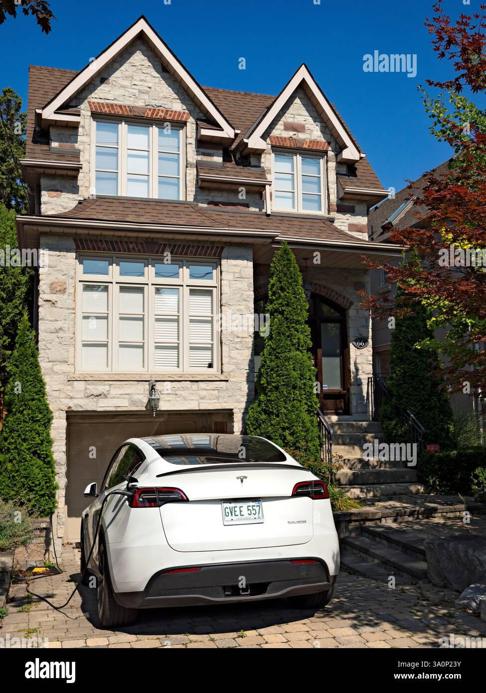 Toronto Canada / A Tesla model 3 charging in driveway of a two storey ...