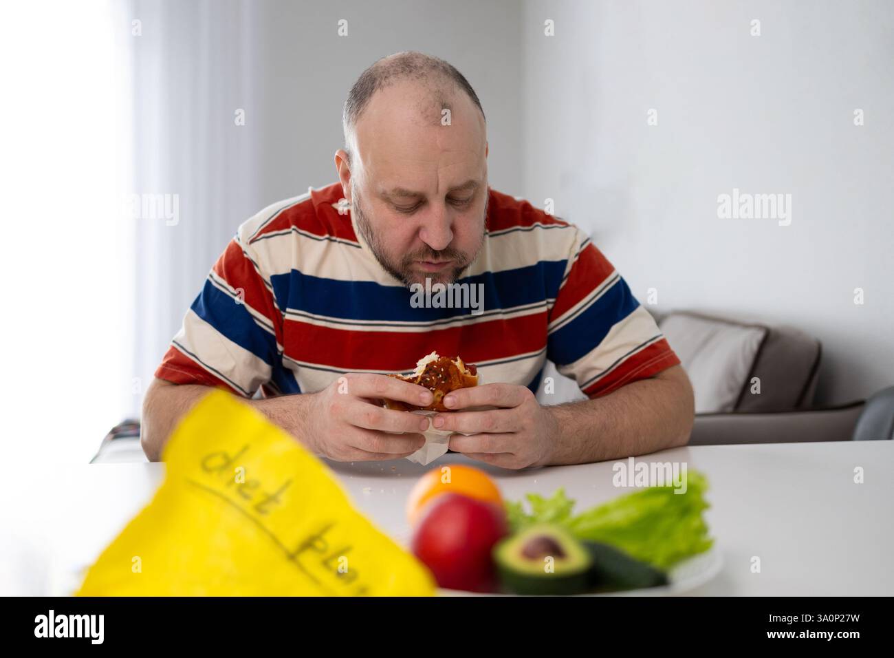 A man sits quietly, contemplating his food choices, carefully balancing ...