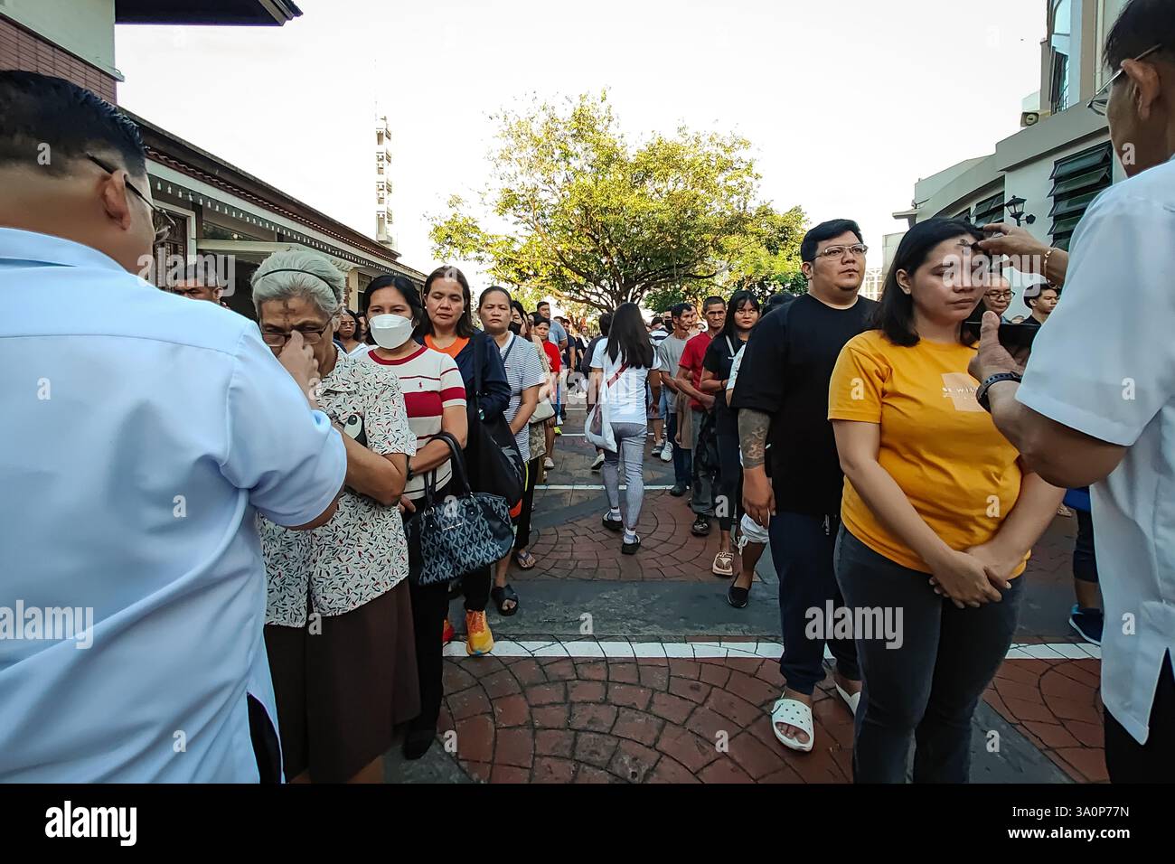 Catholic faithful line up to receive ash marks in the shape of a cross ...