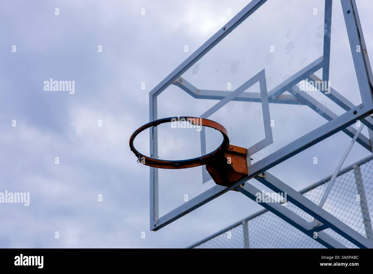 An empty basketball court features a weathered hoop set against a ...