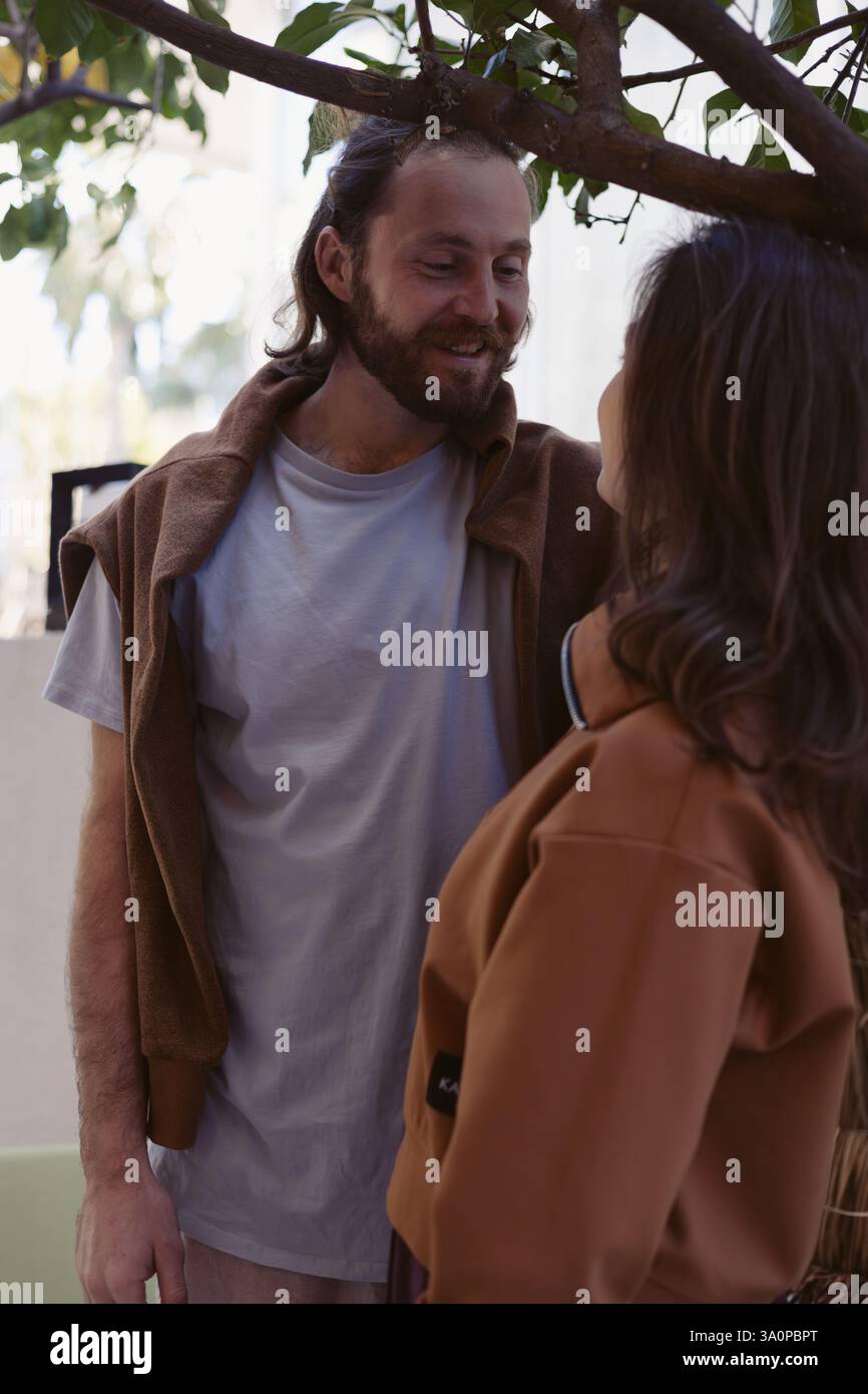 Man and woman stand close together, sharing a joyful conversation ...