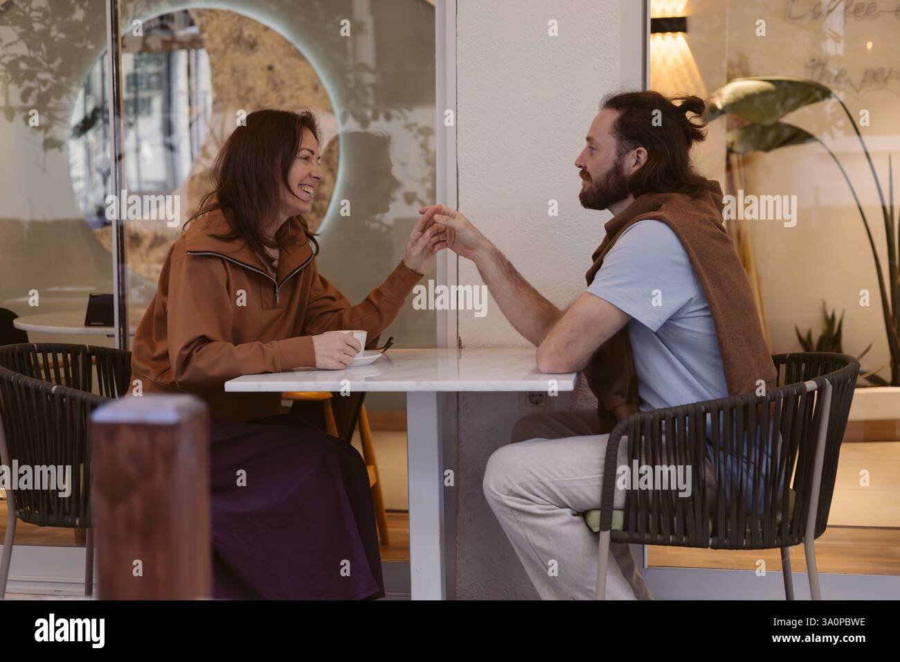 Couple shares a meaningful conversation at a cozy cafe, seated at a small table. They appear ...