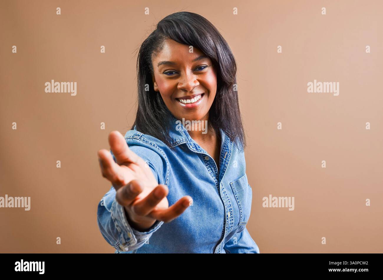 Studio portrait of cheerful young woman extending hand for handshake ...