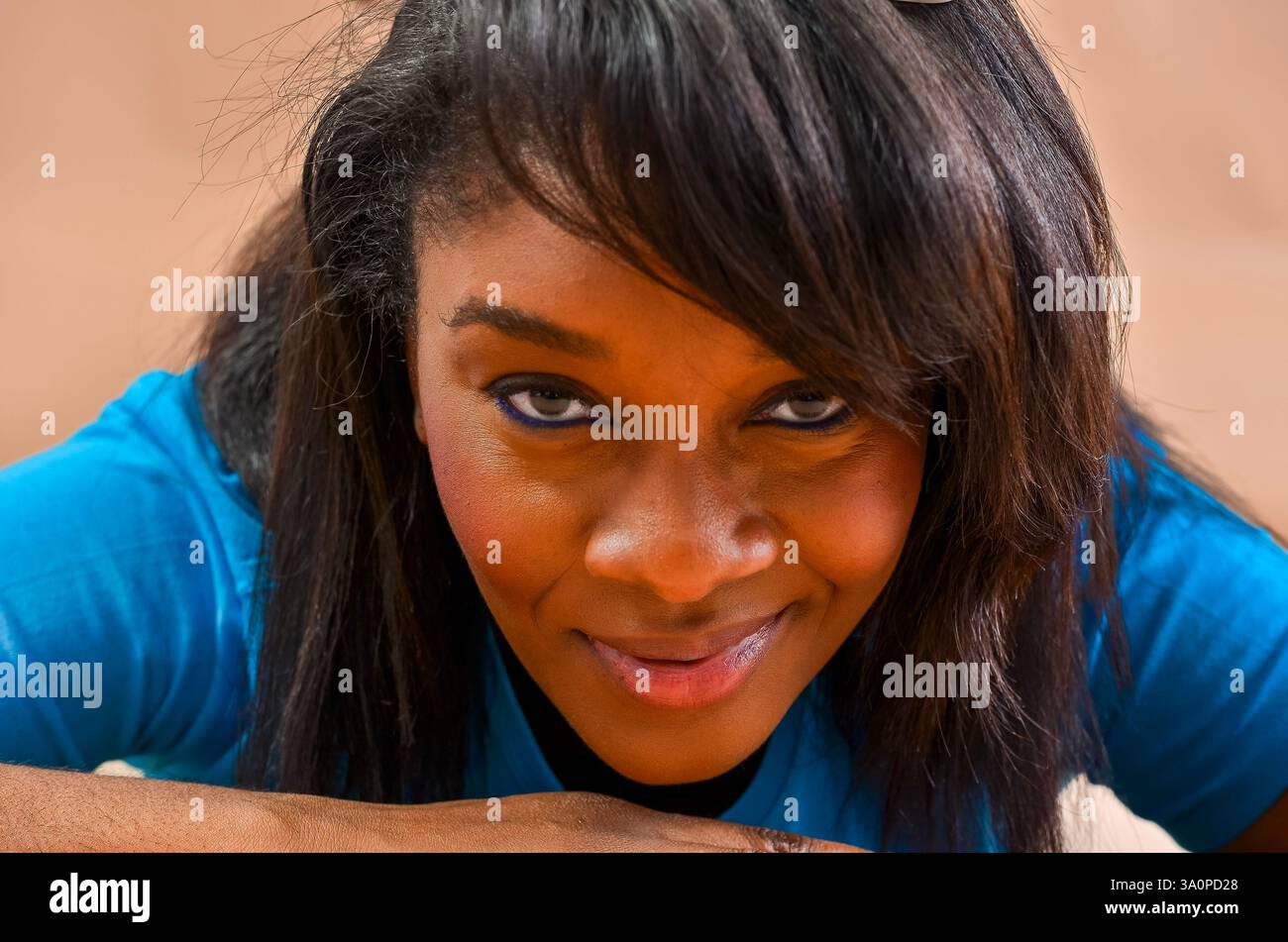 Portrait of a young black woman leaning forward with her chin resting ...