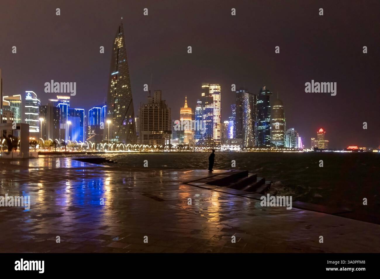 Night view of Doha skyline during rain in Qatar. Silhouette women back ...