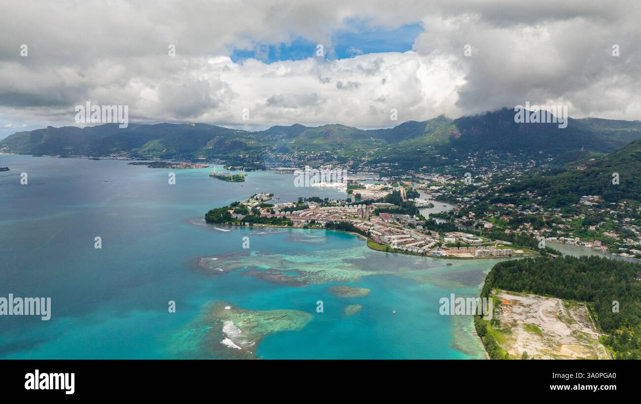 Coastal town with buildings, mountains in the background, and turquoise ...