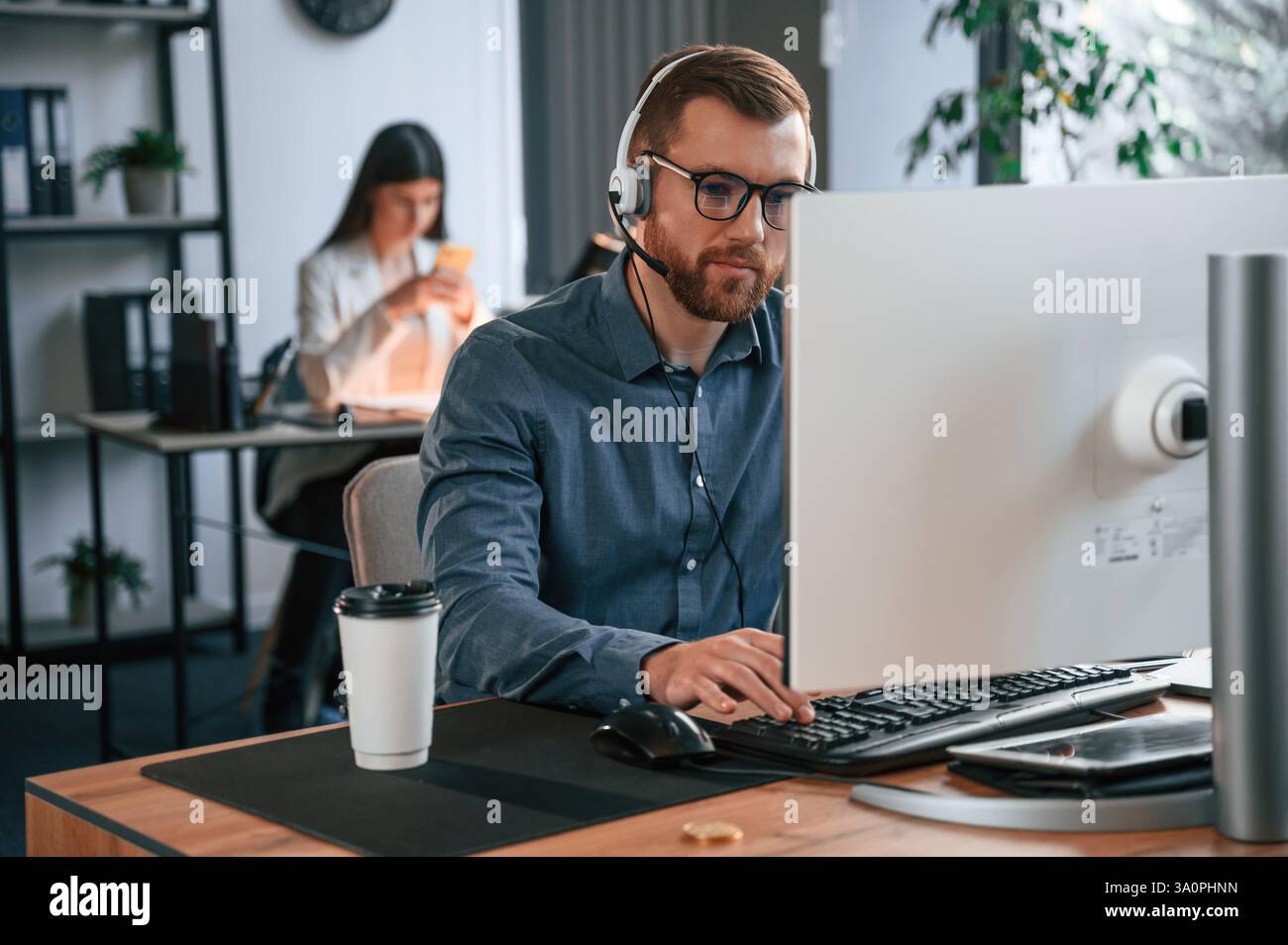 Man is using computer. Two employees are working together in the modern ...