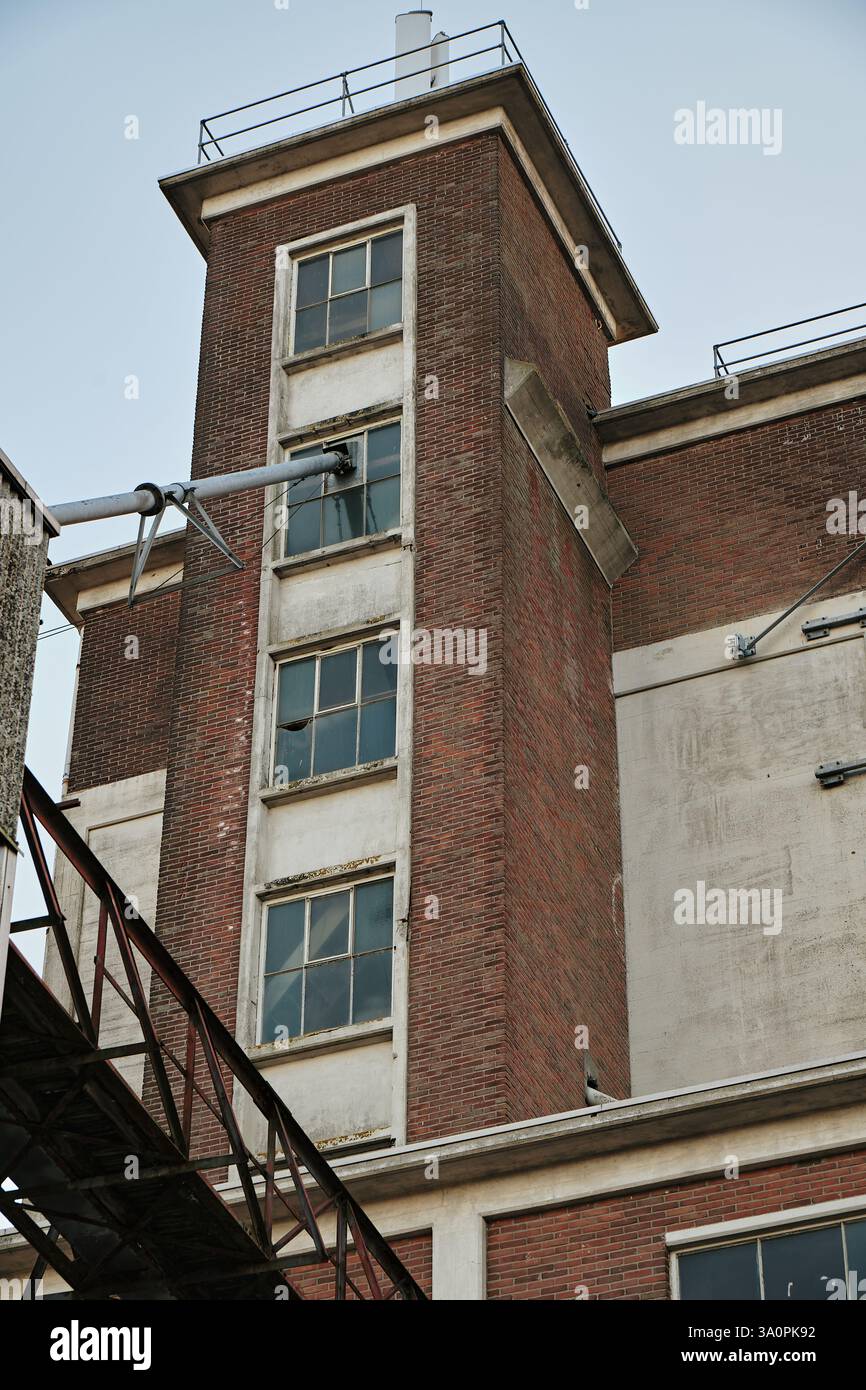 A historic grain silo with a red brick facade, weathered concrete ...