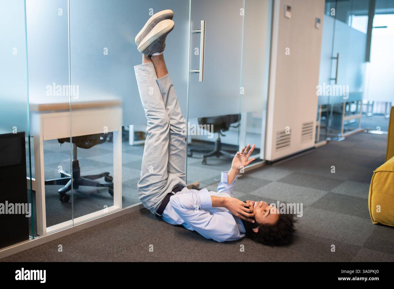 Relaxed man lying on floor with raised legs and using mobile phone in ...