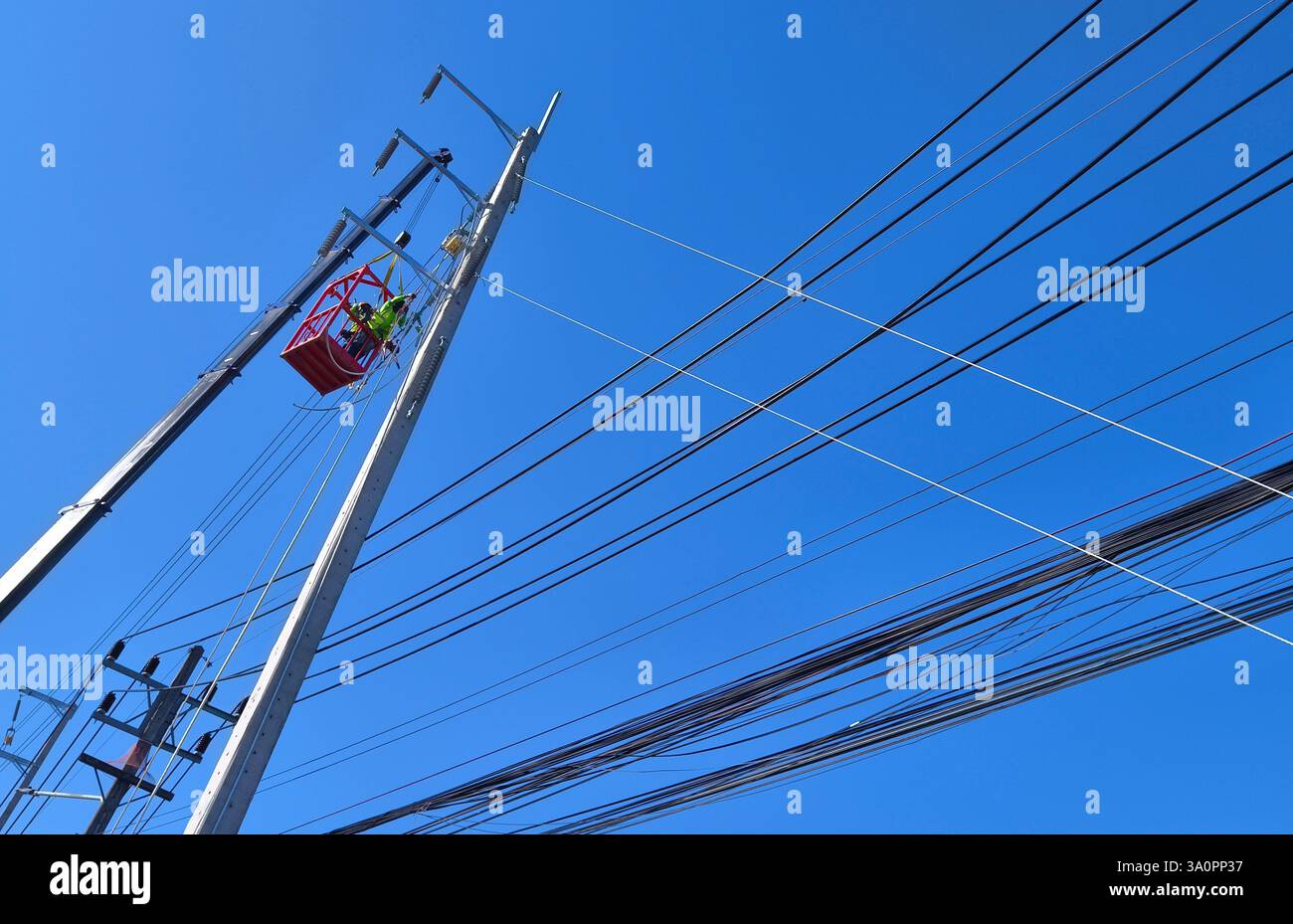 Men in work clothes and hard hats are installing high-voltage wires on ...