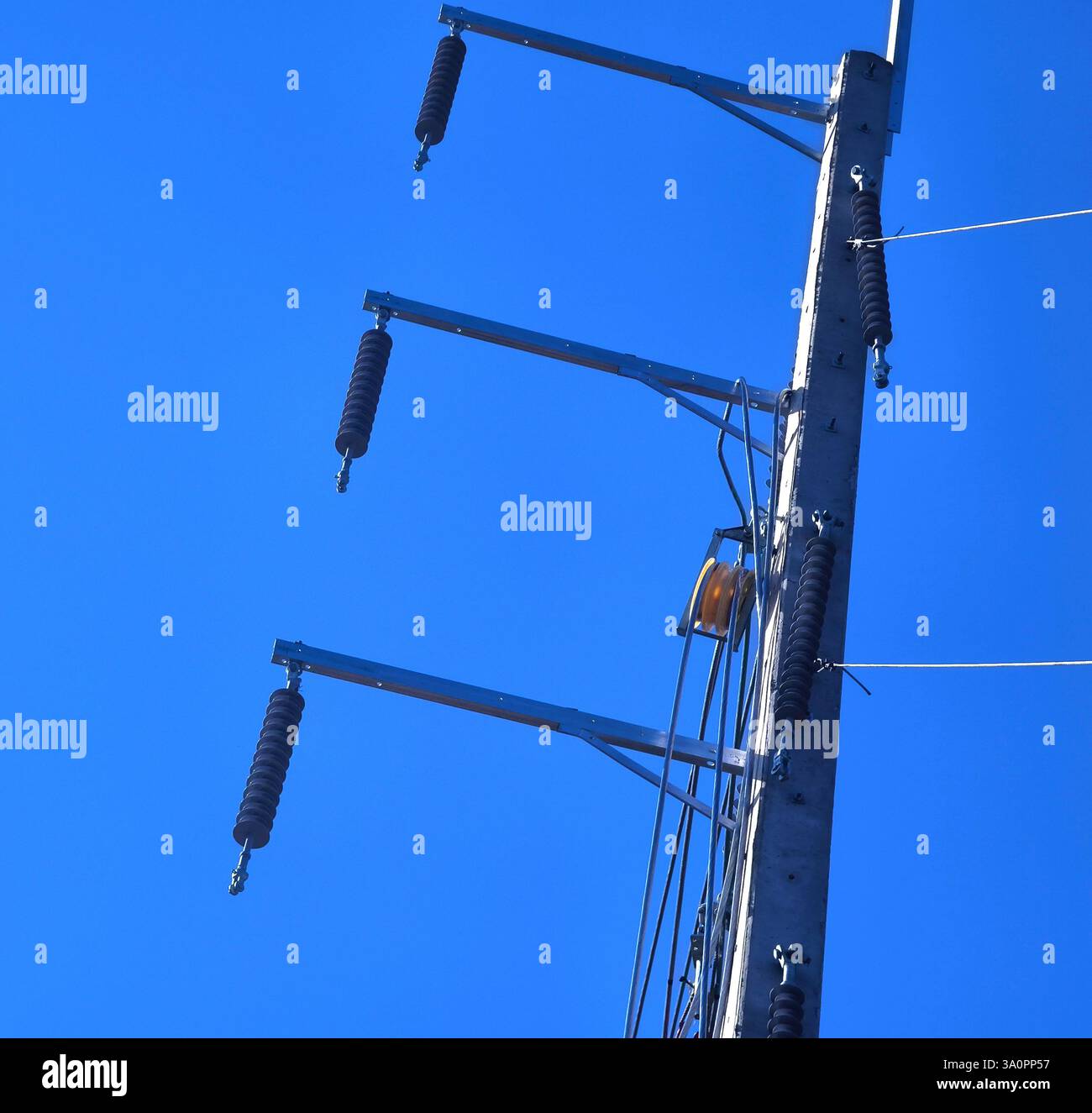 Men in work clothes and hard hats are installing high-voltage wires on ...