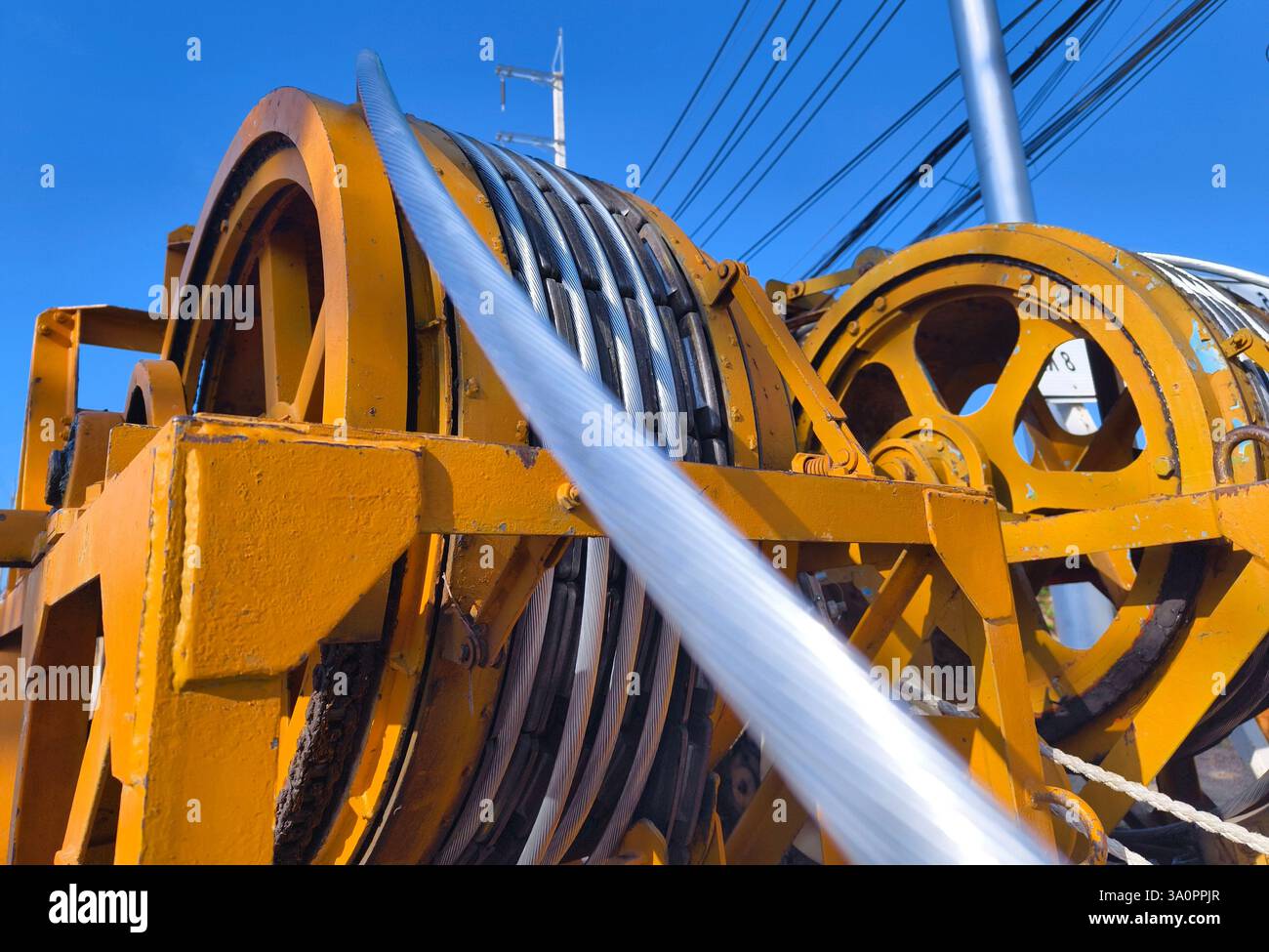 A large wooden spool of high-voltage electric wires is located on the ...