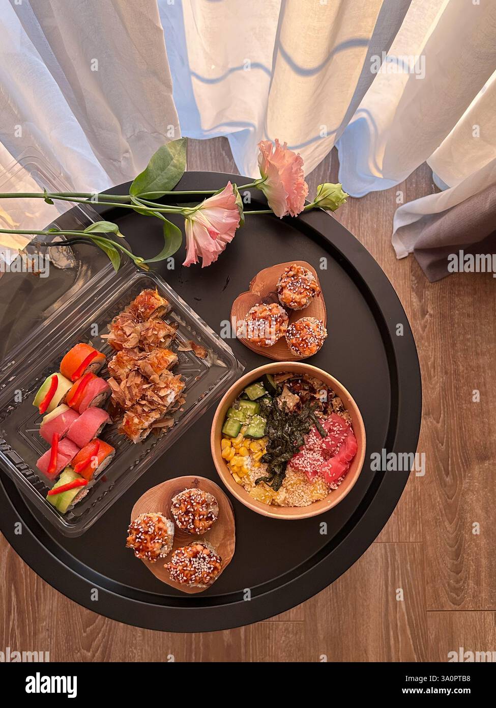 A black round table with a Japanese-style meal including a poke bowl ...