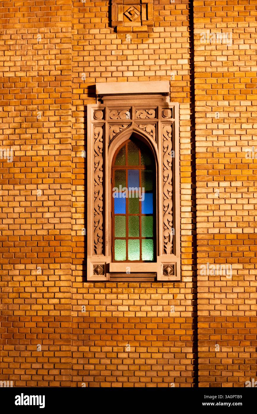 Ornamental stained glass window at night on a yellow brick facade Stock ...